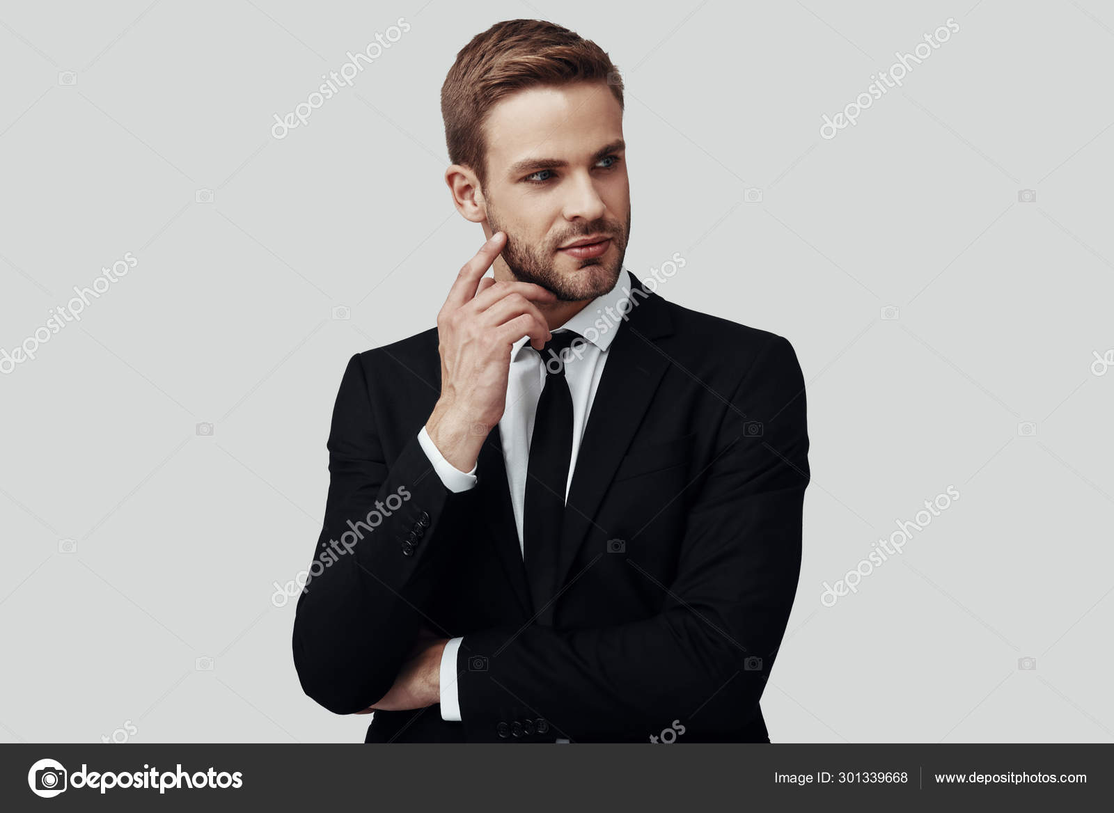 Handsome young man in formalwear looking away while standing against ...