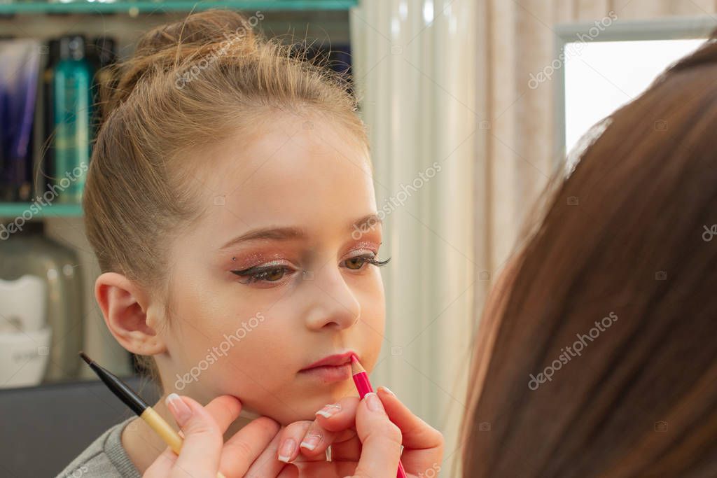 una niña haciendo maquillaje antes de actuar en el escenario ...