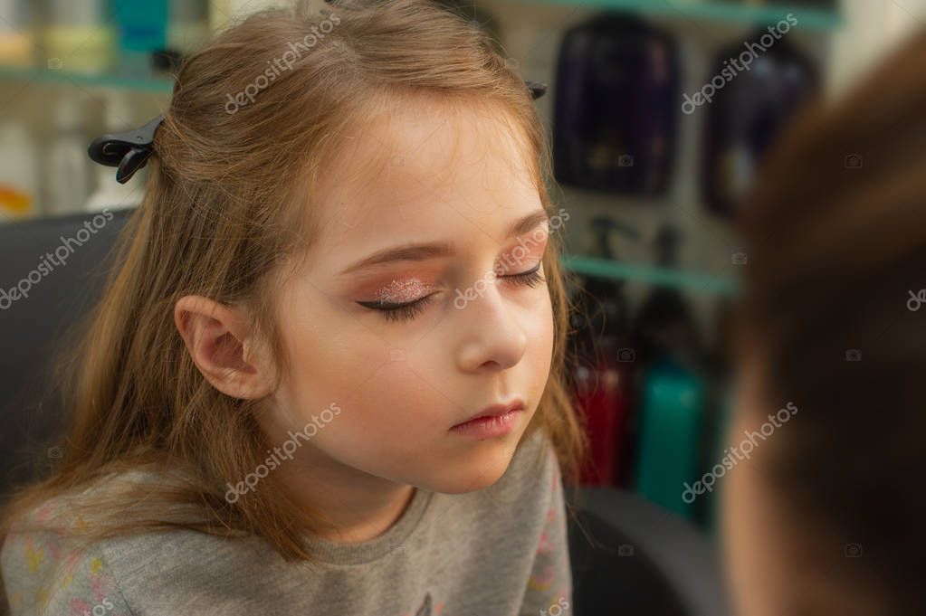 una niña haciendo maquillaje antes de actuar en el escenario ...