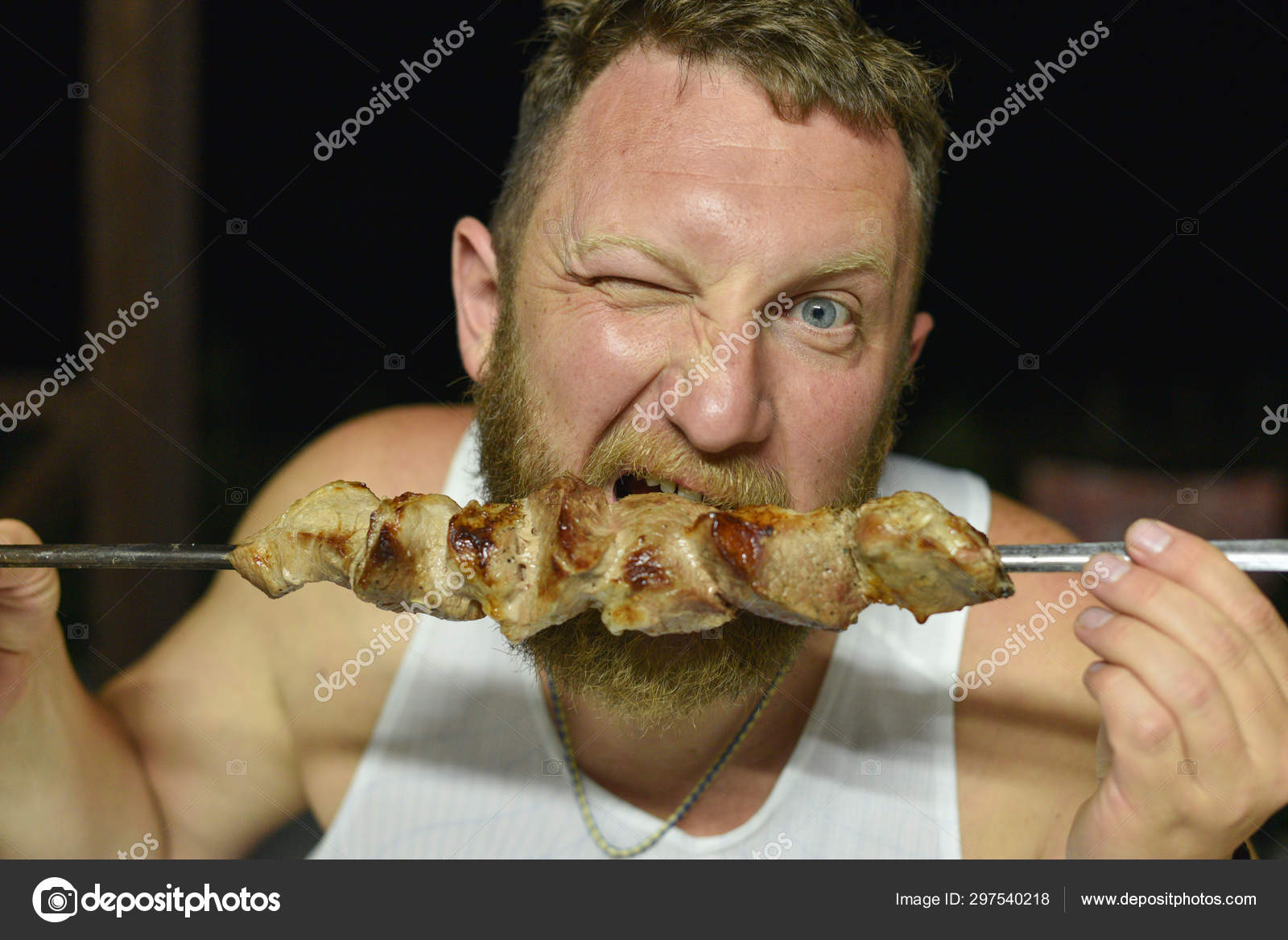 Bearded man eats delicious barbecue. A man with a red beard eats ...