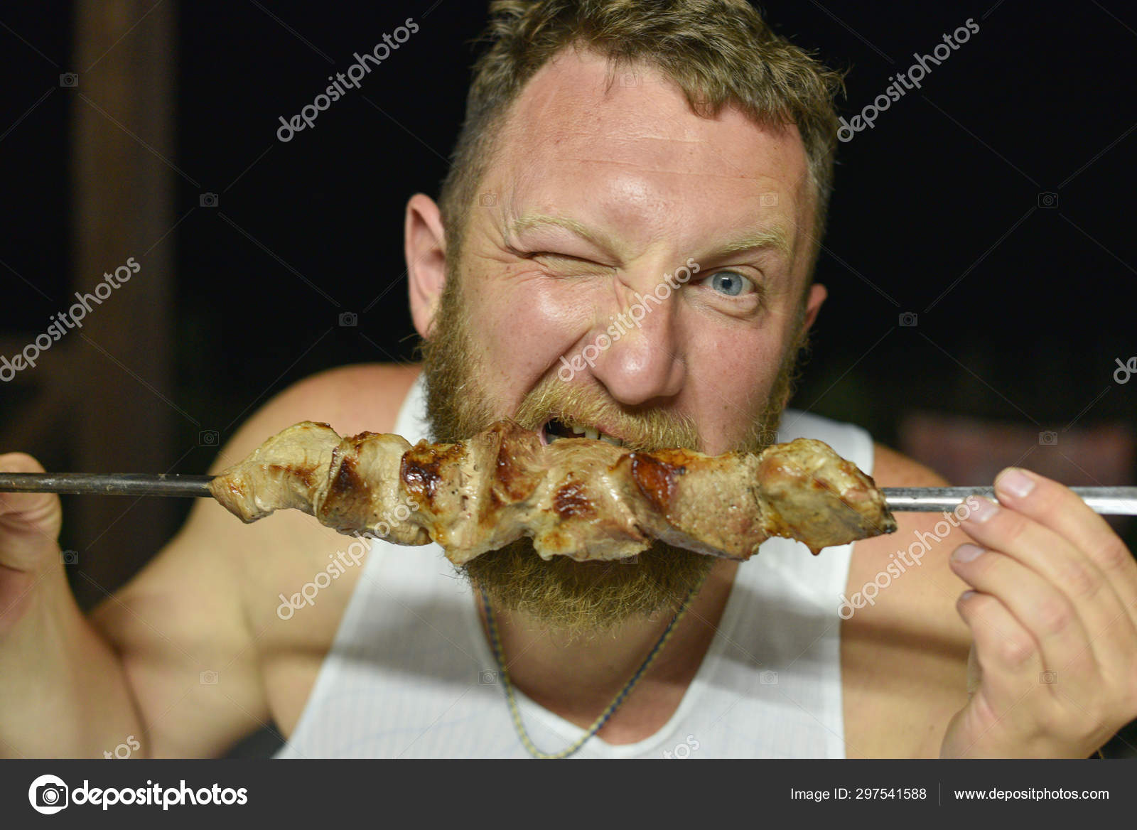 Bearded man eats delicious barbecue. A man with a red beard eats ...