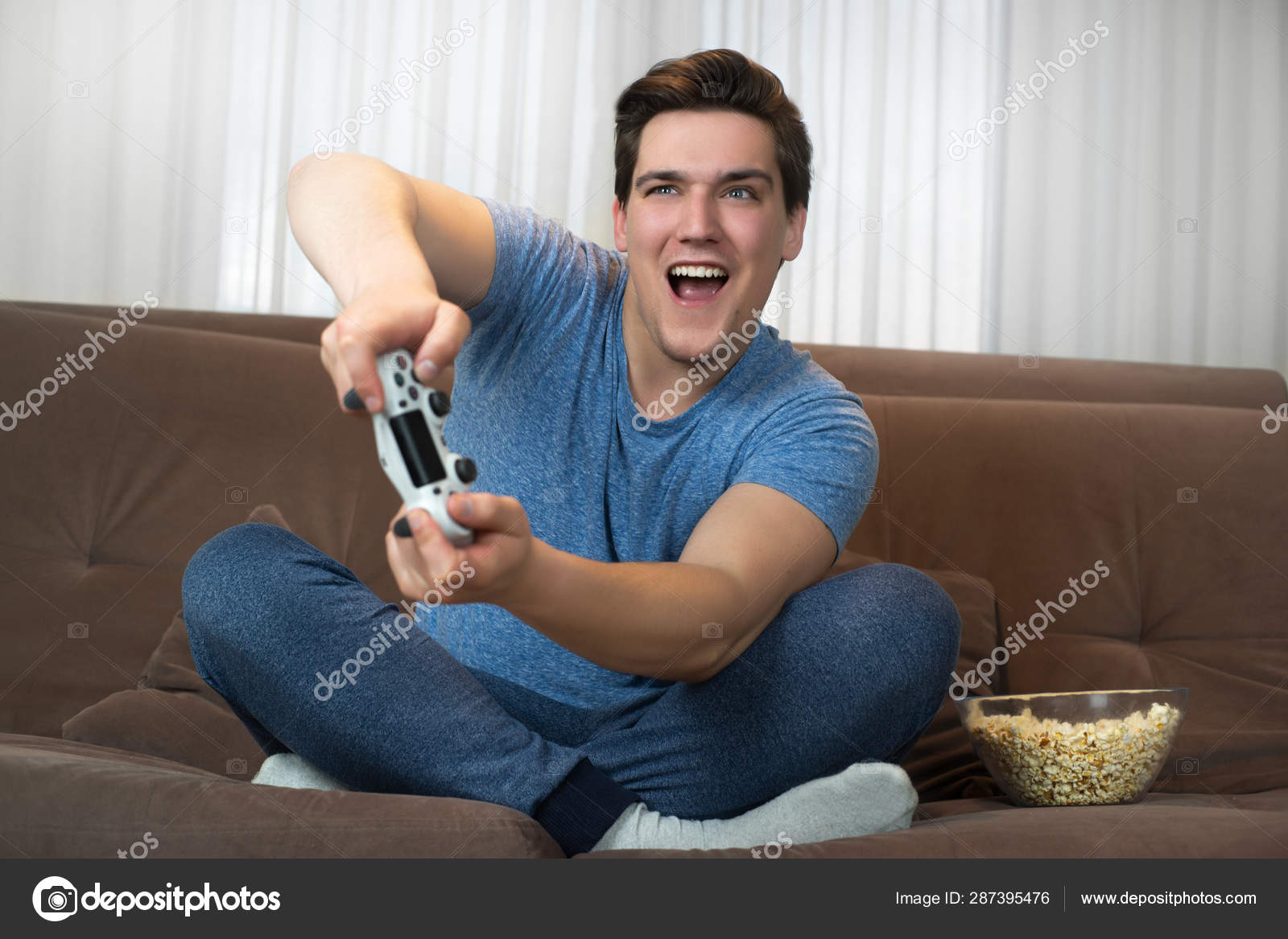 Joven guapo hombre jugando videojuego sentado en cómodo sofá ...