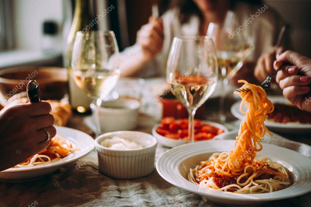 Amigos cenando pasta en casa en un restaurante. 2023