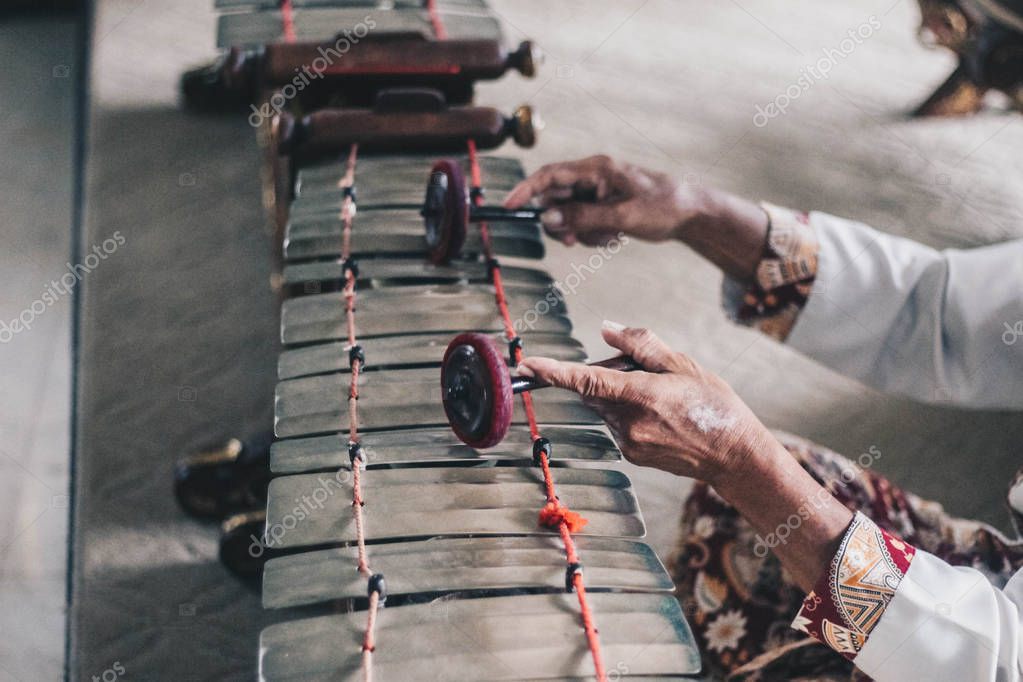 Un hombre usa batik y blankon jugando gamelan Gender o Slenthem ...
