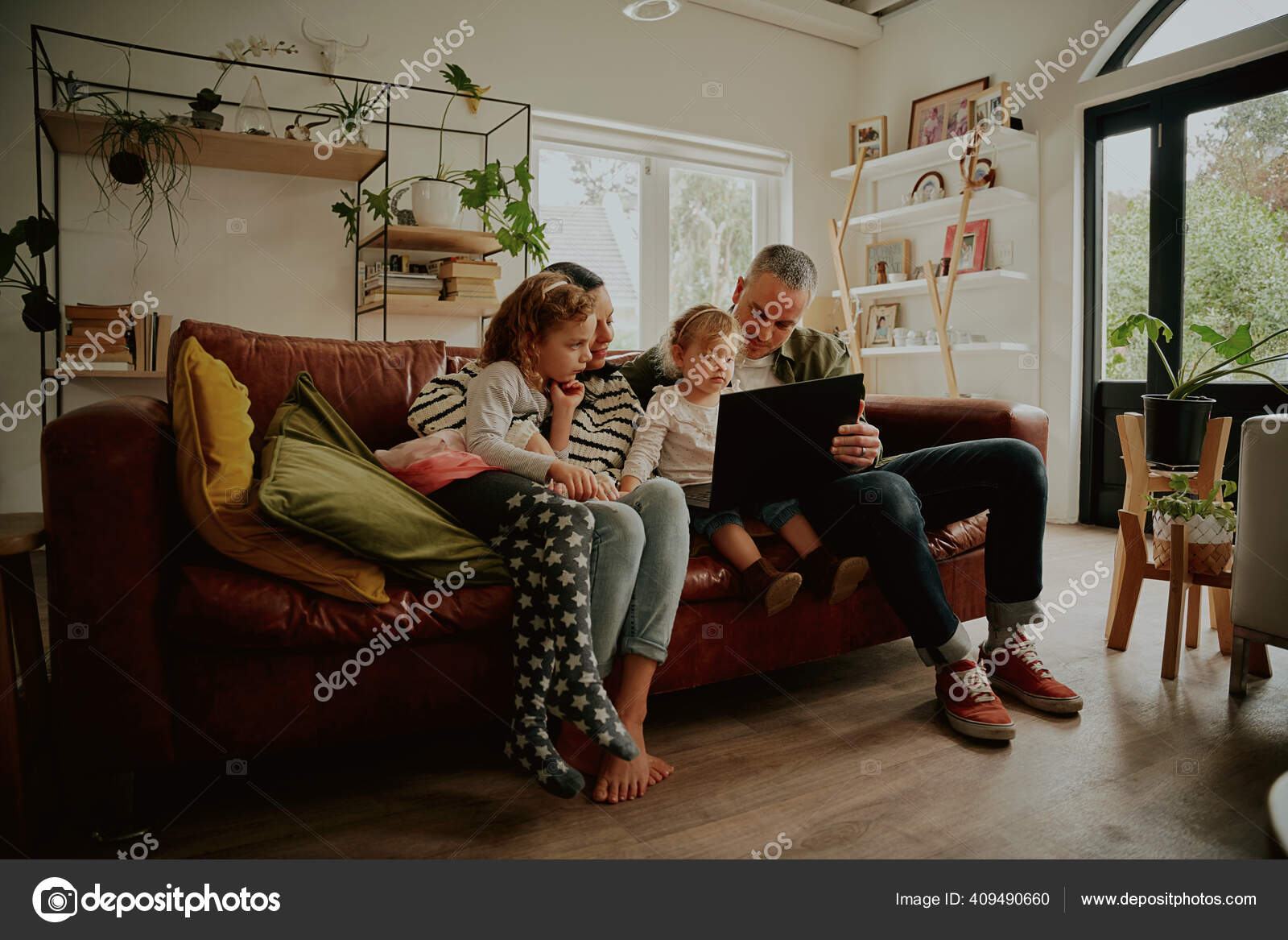 Young family with daughter watching video on laptop while relaxing at ...