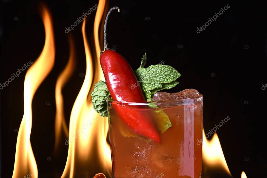 bebida roja exótica con fuego detrás y reflexión sobre backgr negro 2024