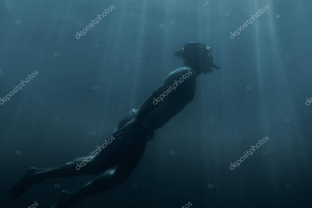 Hombre joven nadando bajo el agua en el mar azul entre los rayos de sol ... Hombre joven nadando bajo el agua en el mar azul entre los rayos de sol ...