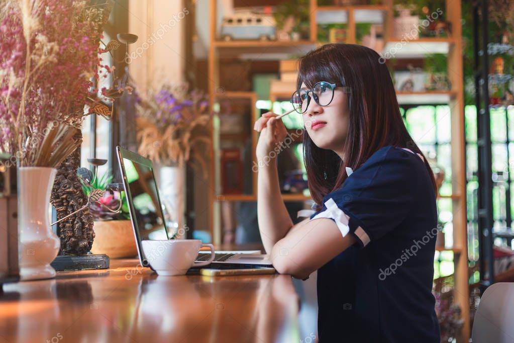Asiática joven mujer de negocios trabajando hacer una nota de algo tomando notas en la cafetería ...