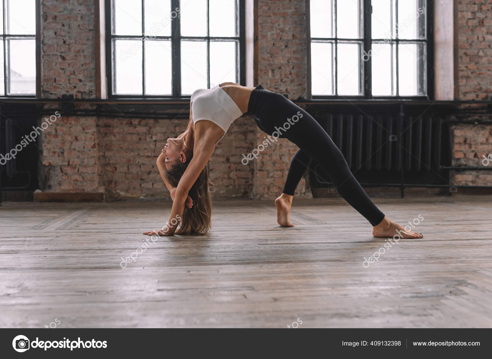 Young woman do complex of stretching yoga asanas in loft style class ...