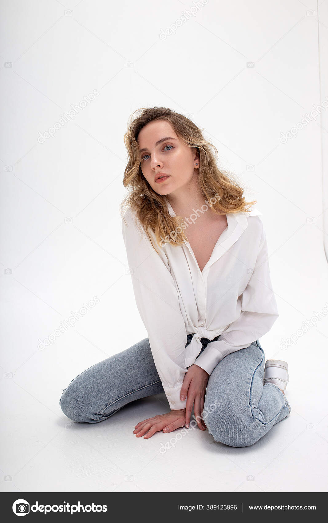 Young Cute Pensive Caucasian Girl Posing In White Shirt Blue Jeans At