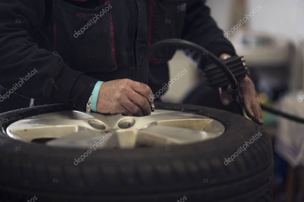 Hombre cambiando neum ticos de coche en el garaje debido a la temporada de invierno. Ajuste de ...