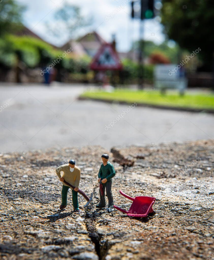 Personas en miniatura, dos obreros reparando una grieta en la carretera ...