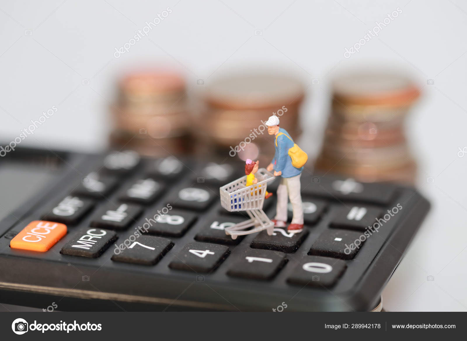Miniature people: shopper and trolley walking on calculator with blur ...