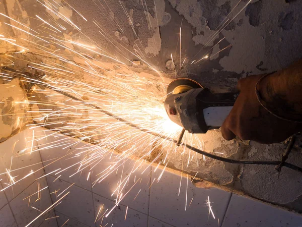Construction Worker cutting iron out of the wall. with grinder. Sparks ...