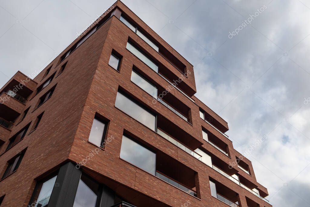 Vista de bajo ángulo de hermosos ladrillos rojos edificio moderno con grandes ventanales y cielo ...