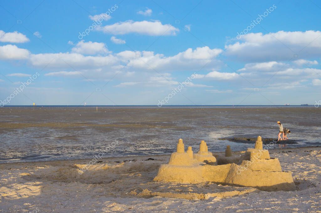 Sandburg am Strand vor Wattenmeer an der Nordsee mit Wolken am blauen ...