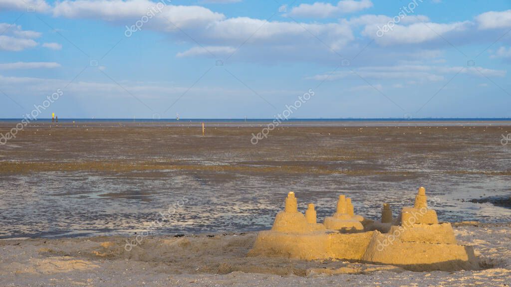 Sandburg am Strand vor Wattenmeer an der Nordsee mit Wolken am blauen ...