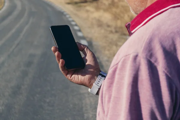 Older man looking at his cell phone on the street. Concept of ...