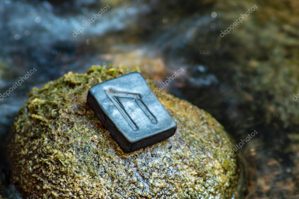Runa nórdica Uruz sobre la piedra y el fondo del río de la tarde. Salud ...