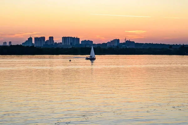 Sailing boat against the sunset behind modern buildings. High quality ...
