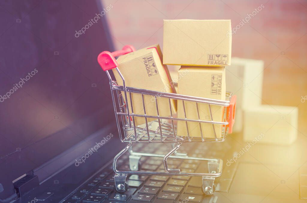 Muchas cajas en un carro en un teclado portátil, sobre fondo de ladrillo. Ideas de compras en ...