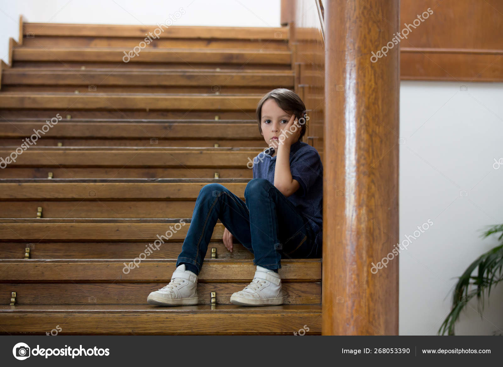 Sad child, sitting on a staircase in a big house, concept for bu ...