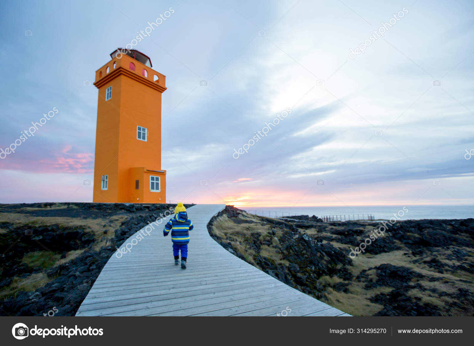 Children running on a path to lighthouse in lava field in beauti ...