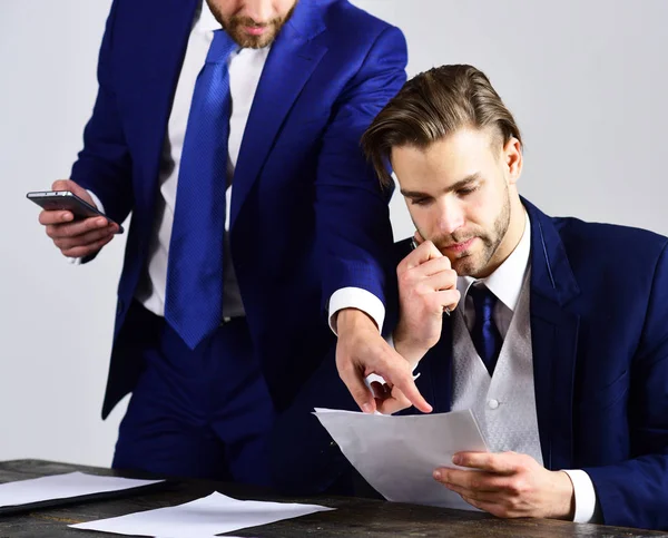 Boss helps young lawyer with documents. Lawyer with smartphone and his ...