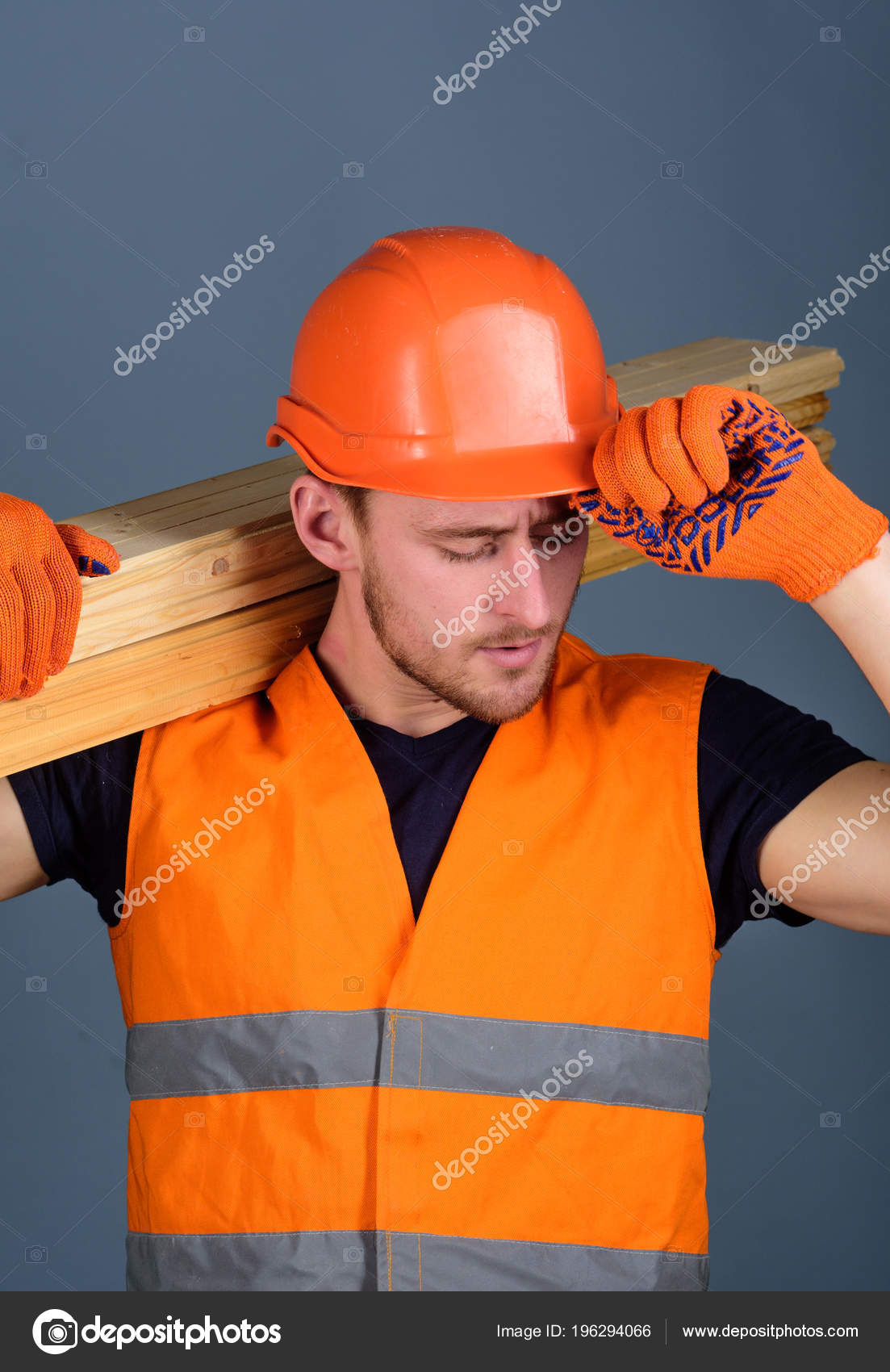Carpenter, woodworker, strong builder on busy face carries wooden beam ...