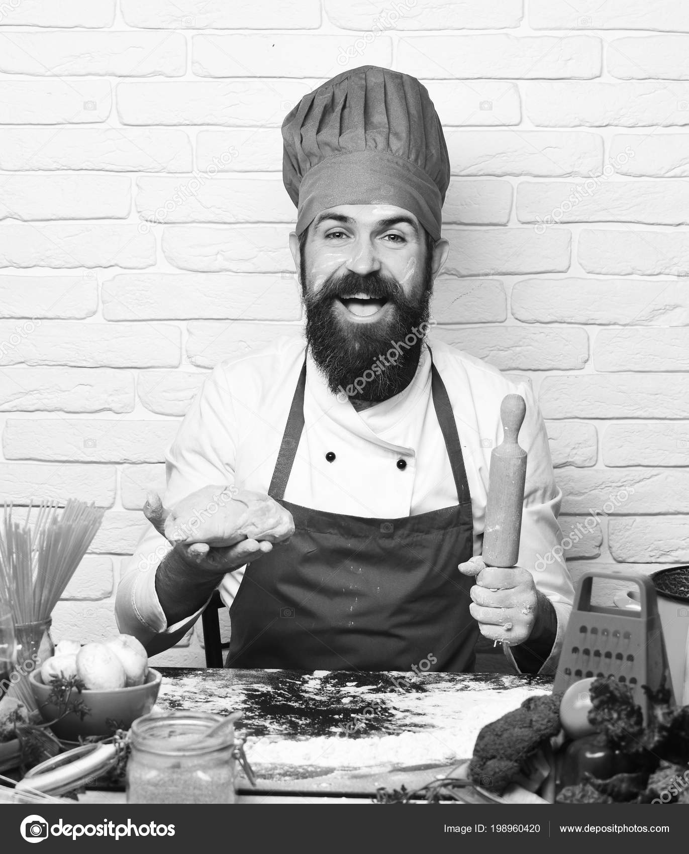 Cook with happy face in burgundy uniform sits by table Stock Photo by ...