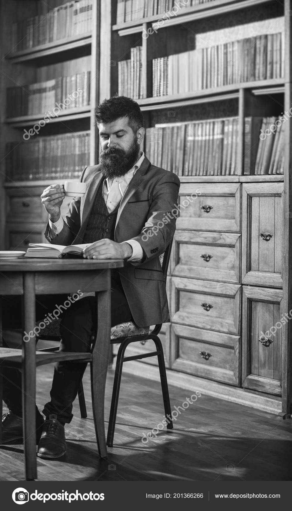Man in classic suit sits in vintage interior, library, book shelves on ...