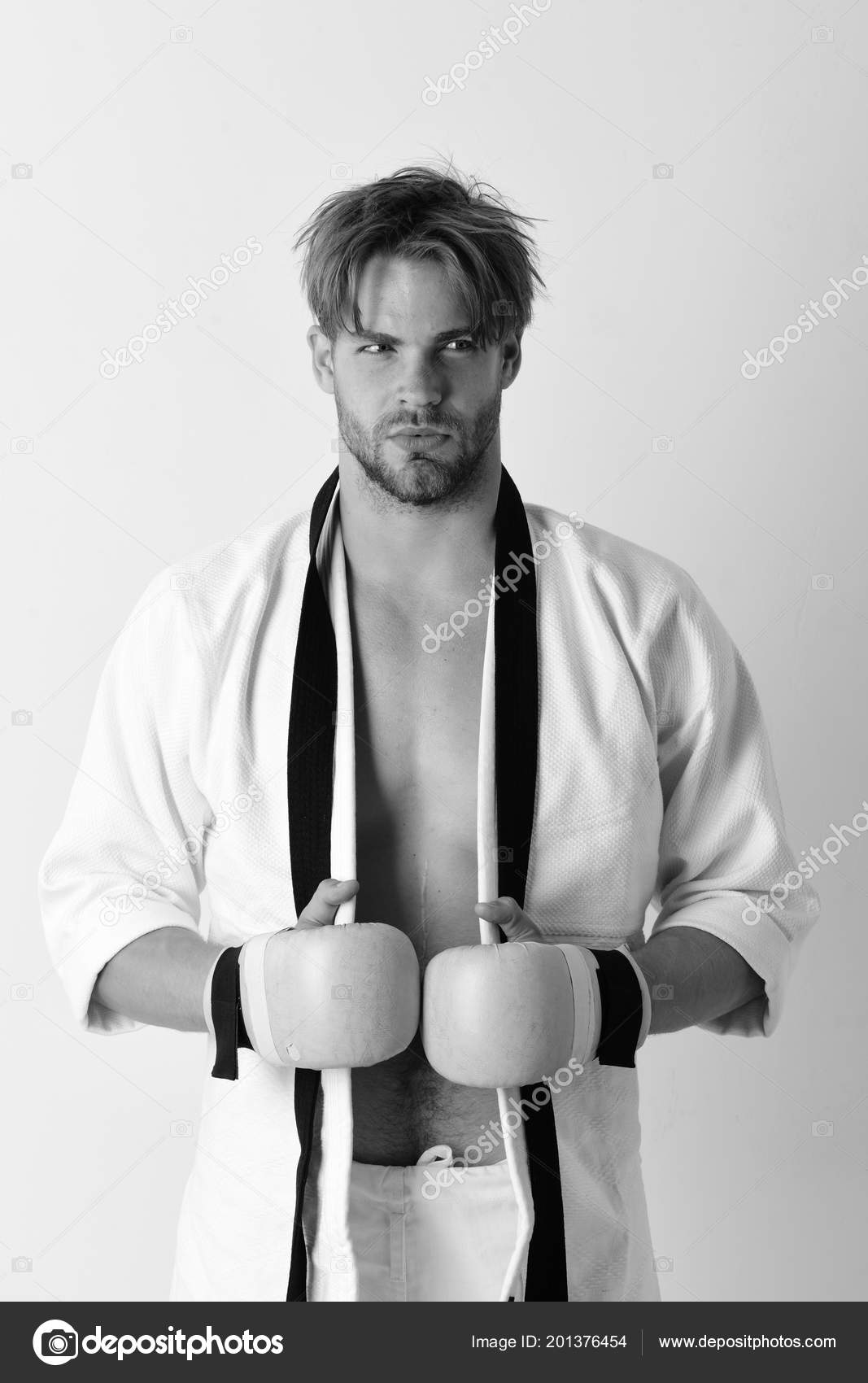 Guy poses in white kimono wearing golden boxing gloves. MMA fighter ...