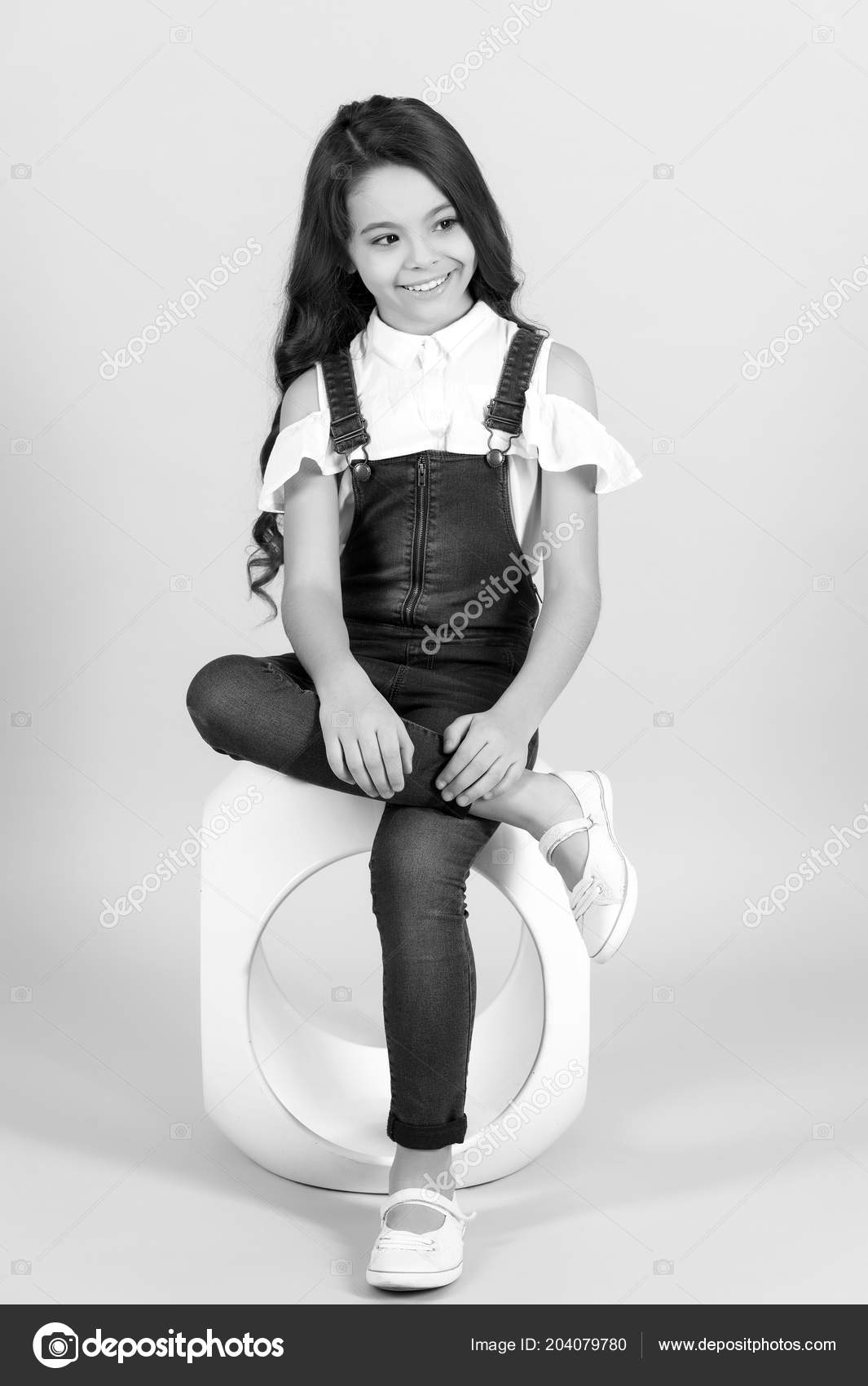 Child model in jeans overall sit leg crossed on chair — Stock Photo ...