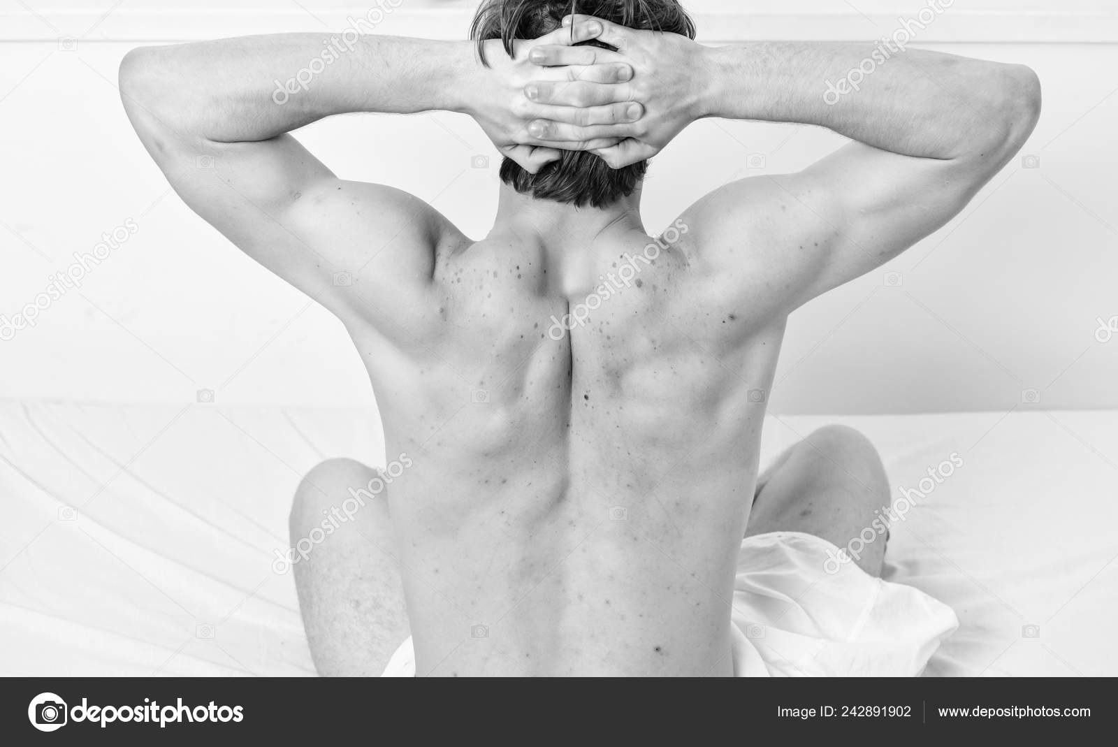 Young man stretching while waking up in the morning. Cheerful young man is waking up after ...