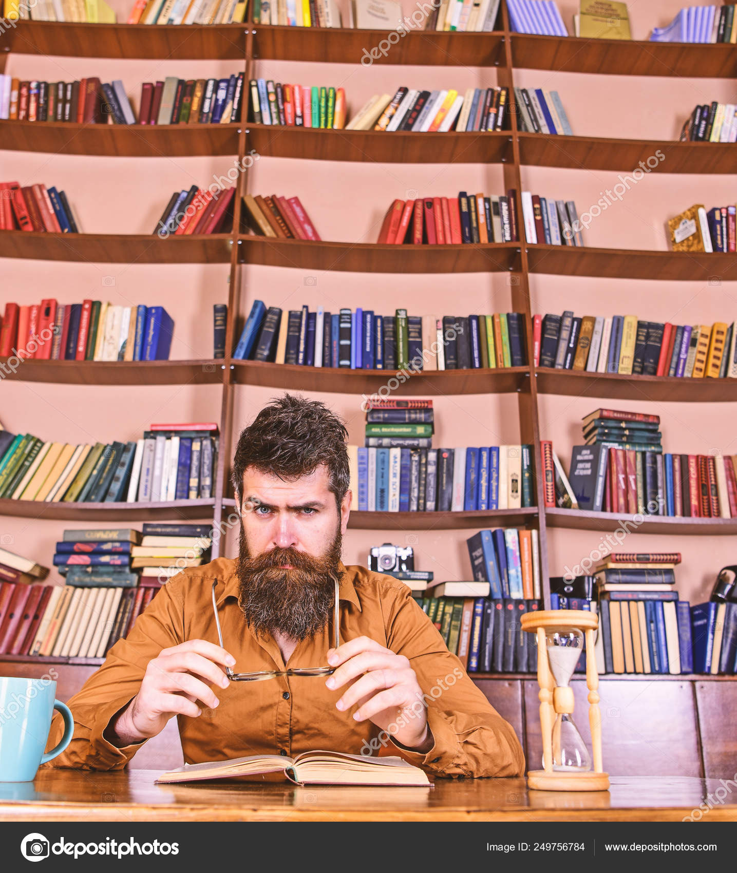 Man on busy face reading book, bookshelves on background. Education and ...