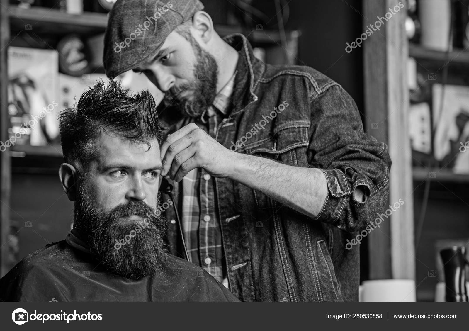 Barber in denim jacket busy with trimming hipster, barbershop ...