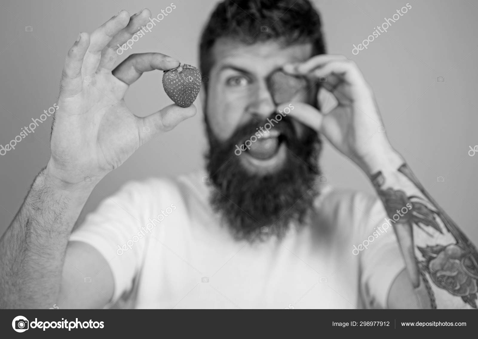 Man bearded winking with red berry, defocused. Perfect strawberry ...
