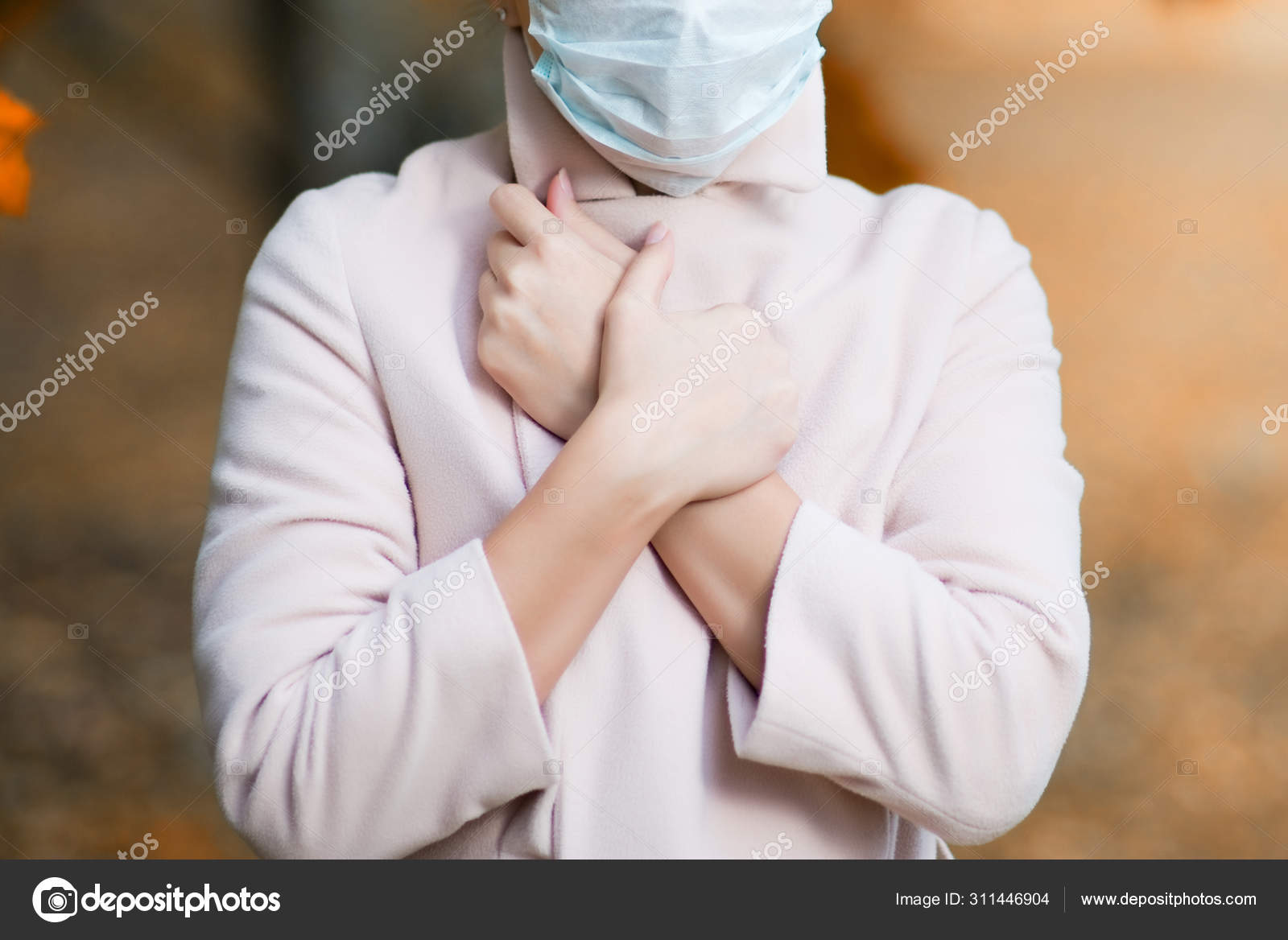 Woman's hands in a coat folded on her chest against the background of ...