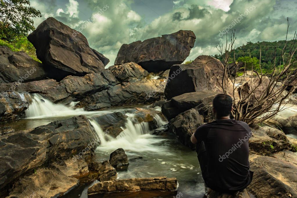 hombre sentado en la roca observando el hermoso arroyo cascada larga ...