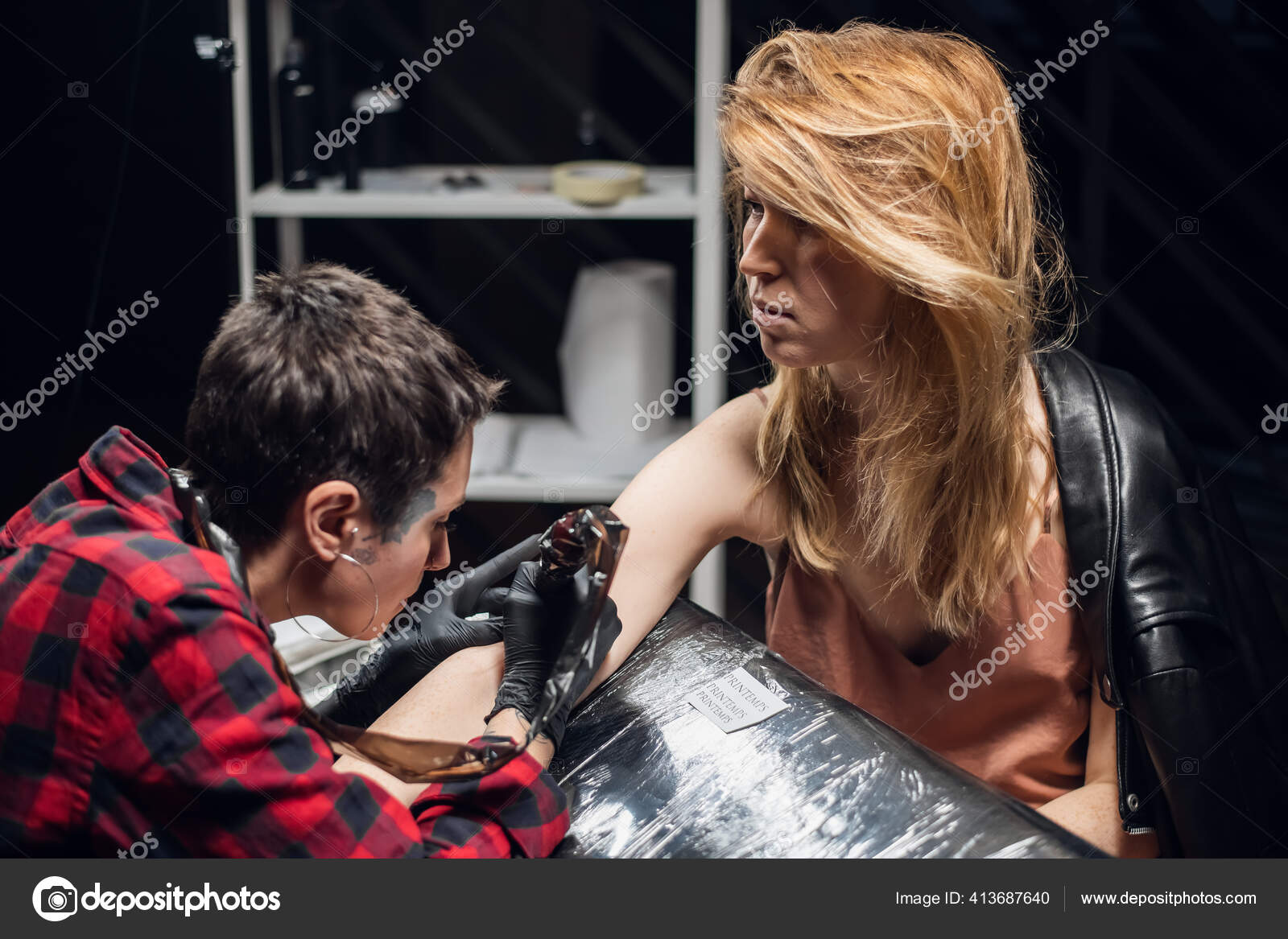 Modern experienced girl tattoo master makes a tattoo on the arm of a ... Modern experienced girl tattoo master makes a tattoo on the arm of a ...