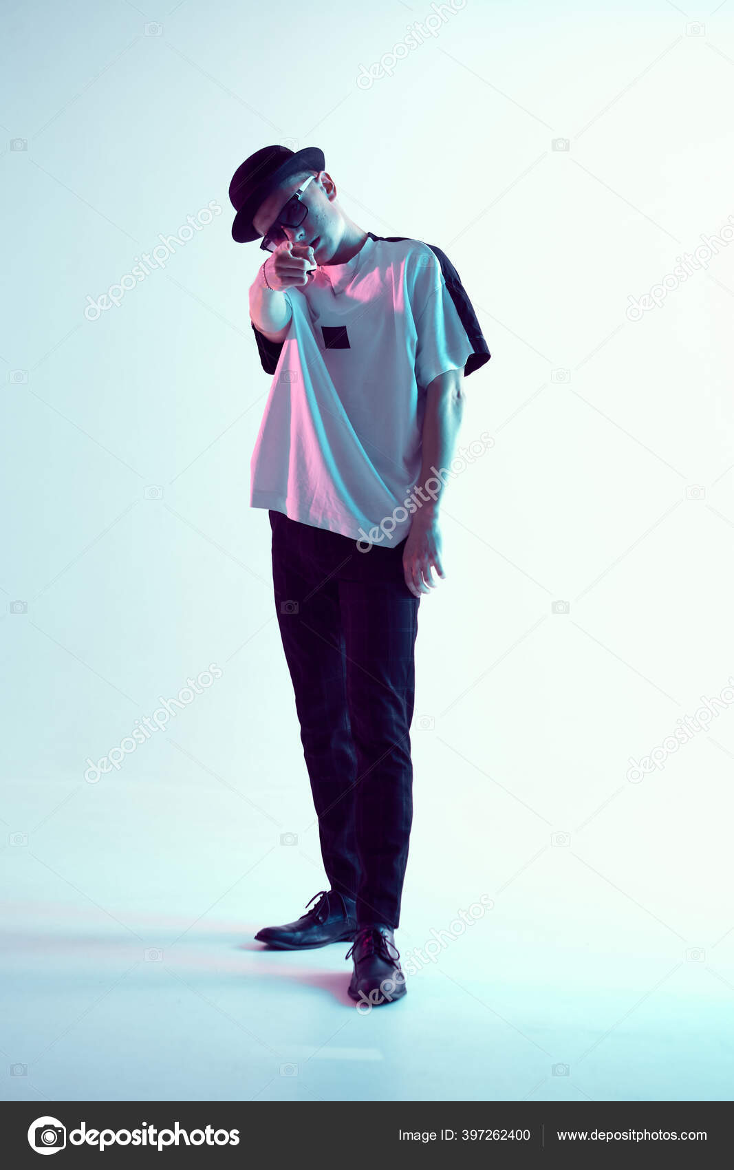 Stylish young breakdancer guy in hat and sunglasses stands in neon ...