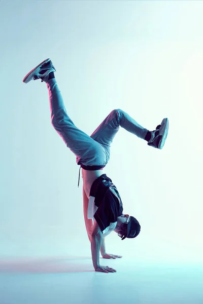 Stylish young guy breakdancer in cap covering face with hands stands on ...