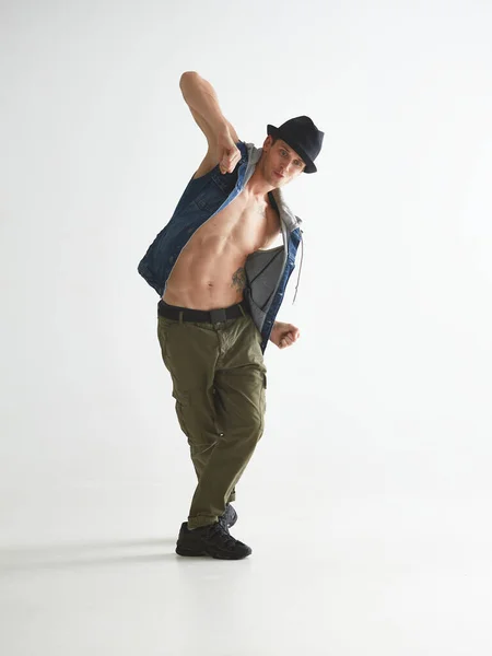 Stylish young guy breakdancer in cap covering face with hands stands on ...
