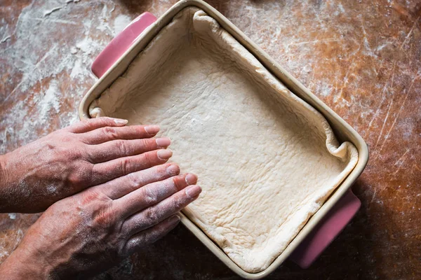 Fresh raw cake batter on a ceramic baking tray, womens hands painted in ...