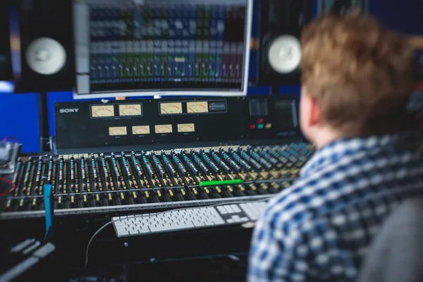 Sound editor engineer working at studio with mixing panel, mixing music ...