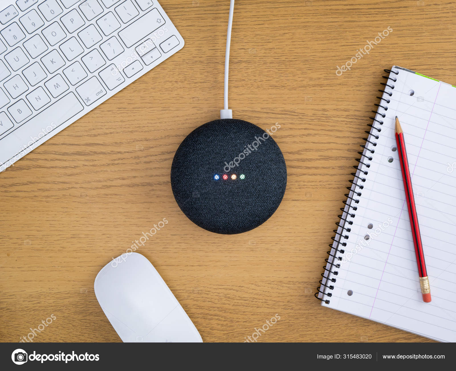 Smart home device speaker lit up on wooden desk table with notepad ...