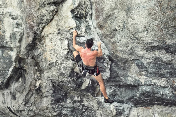Young male climber climbing a rock wall without safety rope - Stock ...