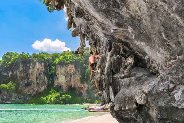 A man climbs on a cliff without a safety rope above the sea - Stock ...