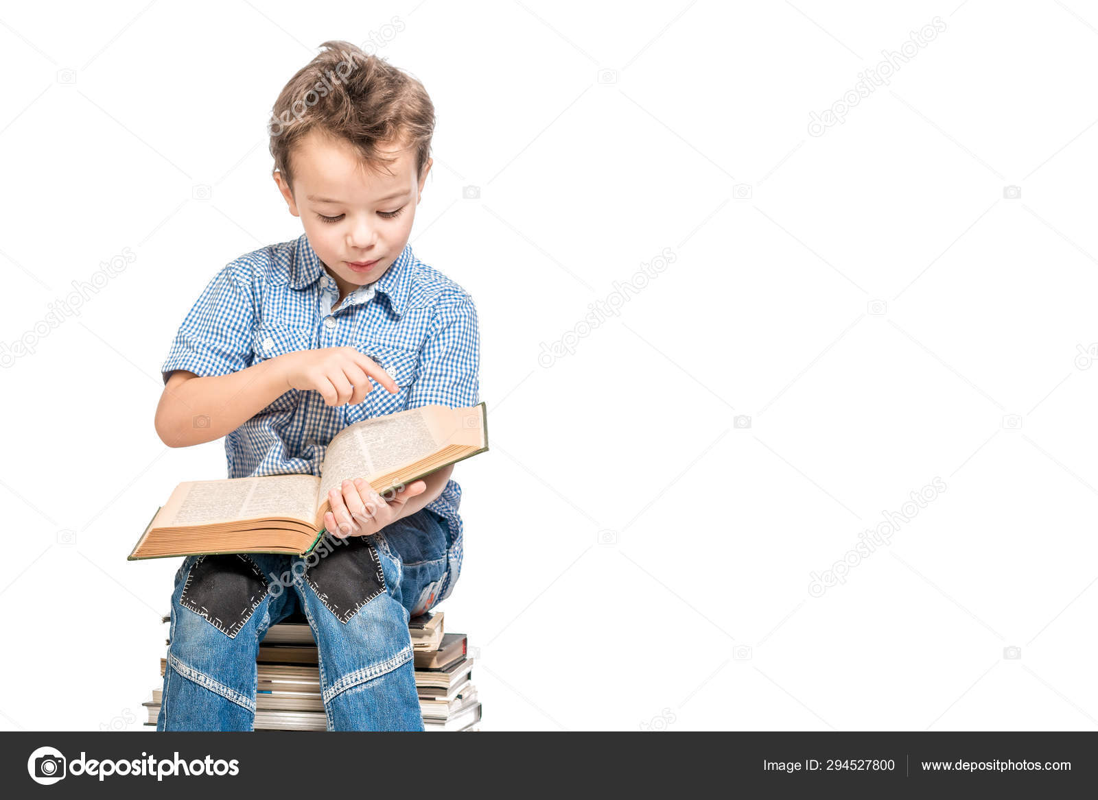 Cute boy sitting on a pile of books and reading a book on a whi Stock ...