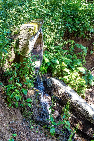 From a reinforced concrete sewer pipe that runs under the road, water ...